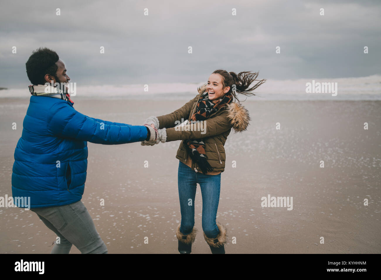 A young couple laugh and dance on Tynemouth beach in winter Stock Photo ...