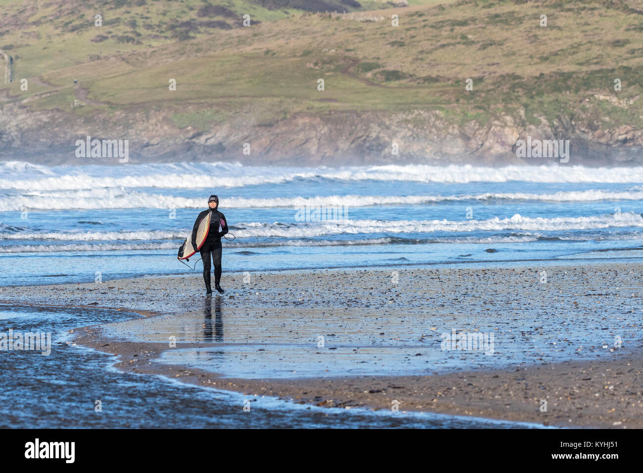 Polzeath surfing - a surfer walking out of the sea on Polzeath Beach on ...