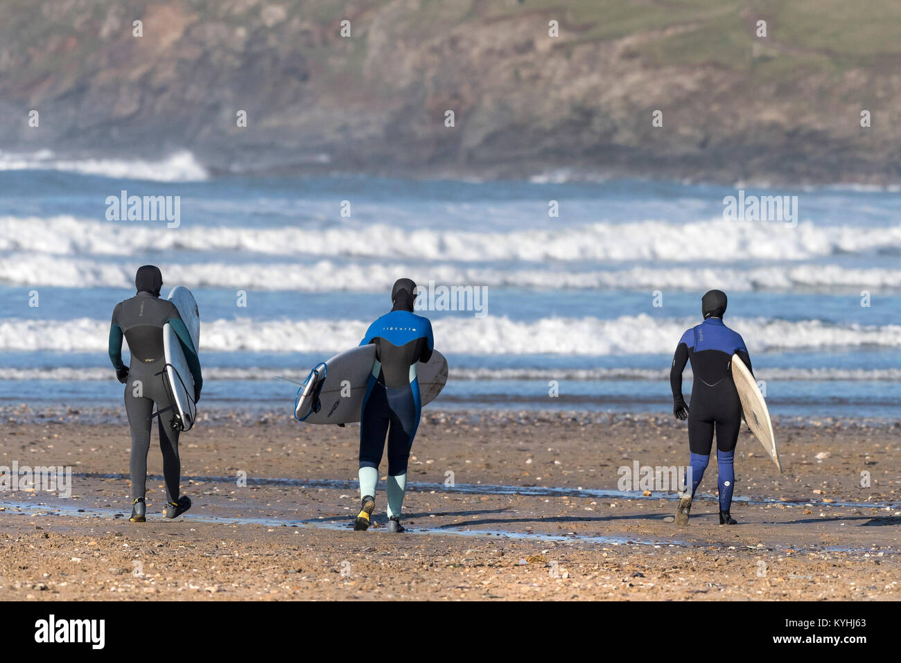 Polzeath surfing - Three surfers carrying their surfboards and walking ...