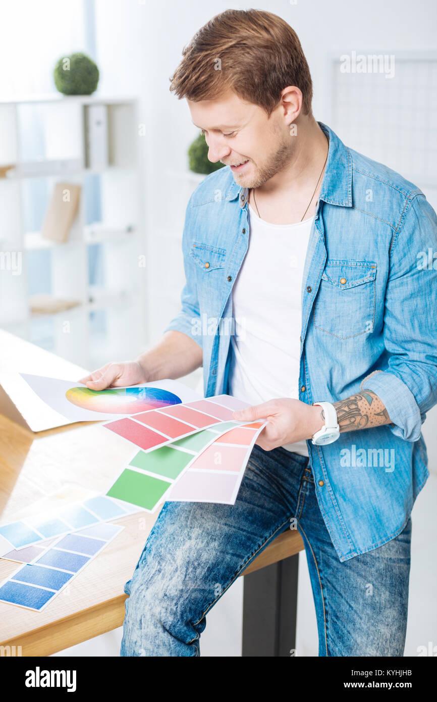 Young man sitting on the table and looking at color palettes Stock ...