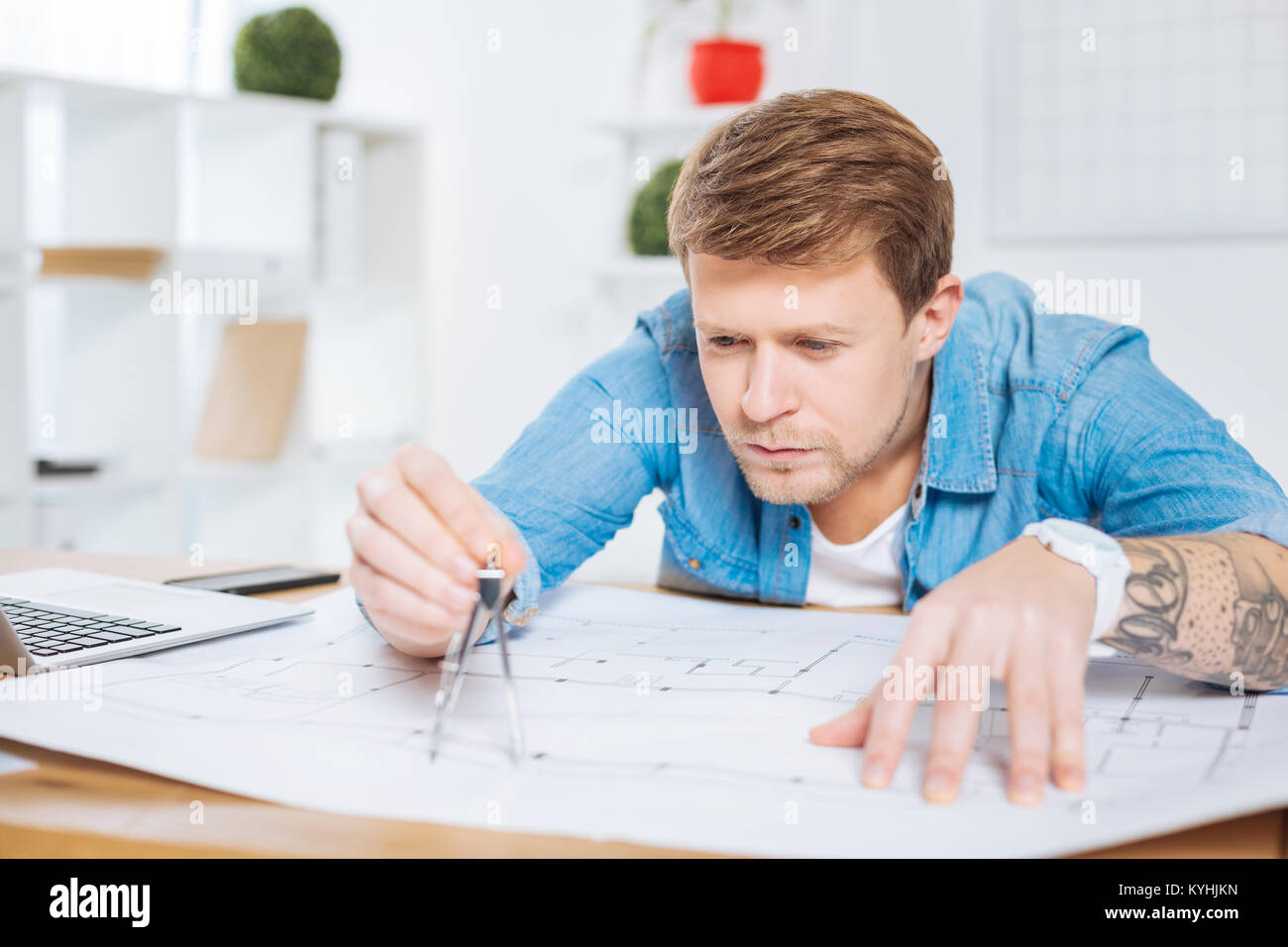 Concentrated man measuring the length while holding compasses Stock ...
