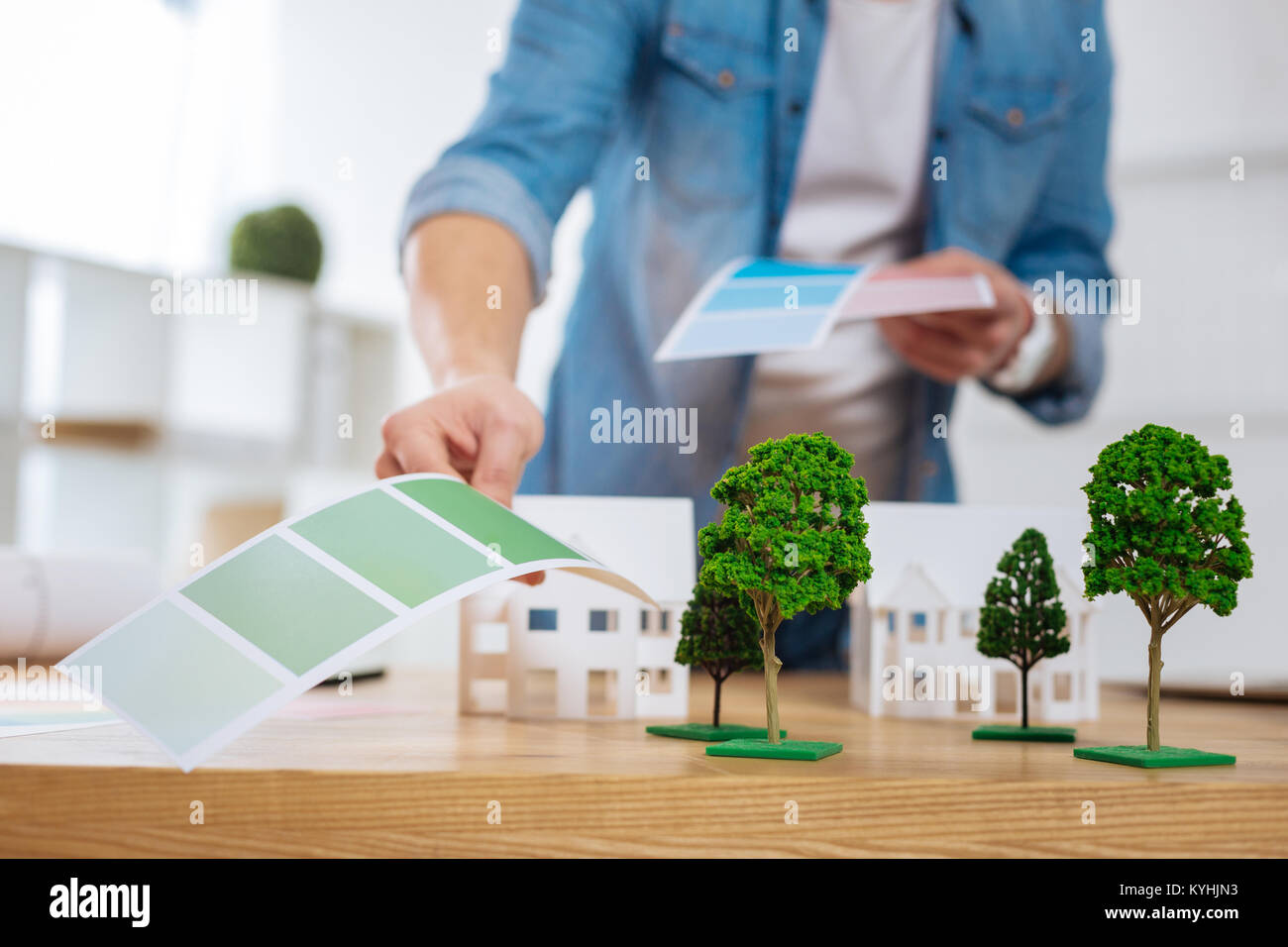 Smart engineer putting green color palette to a miniature tree while ...