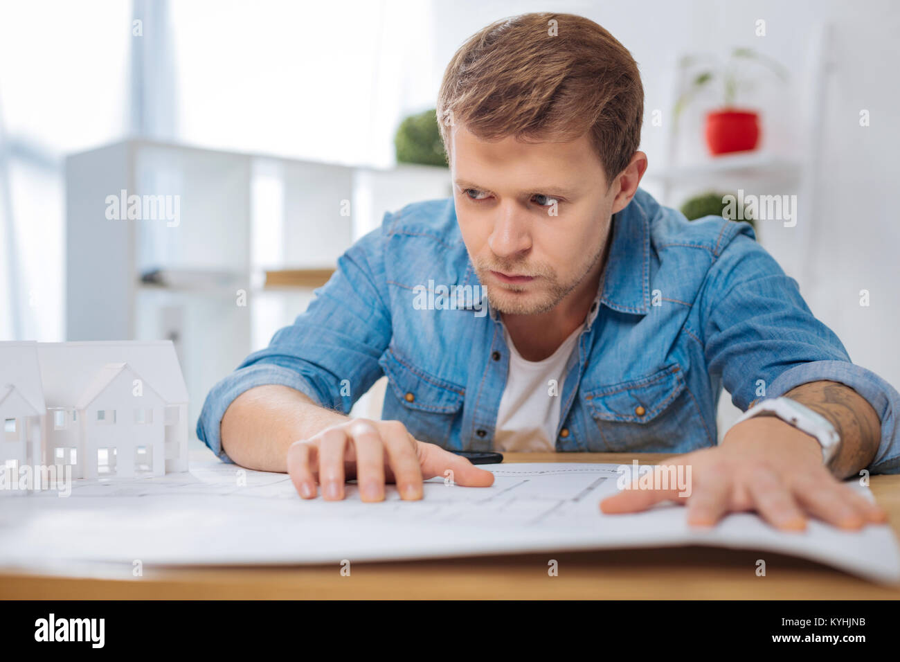 Serious engineer putting his hands on a scheme while thinking Stock ...