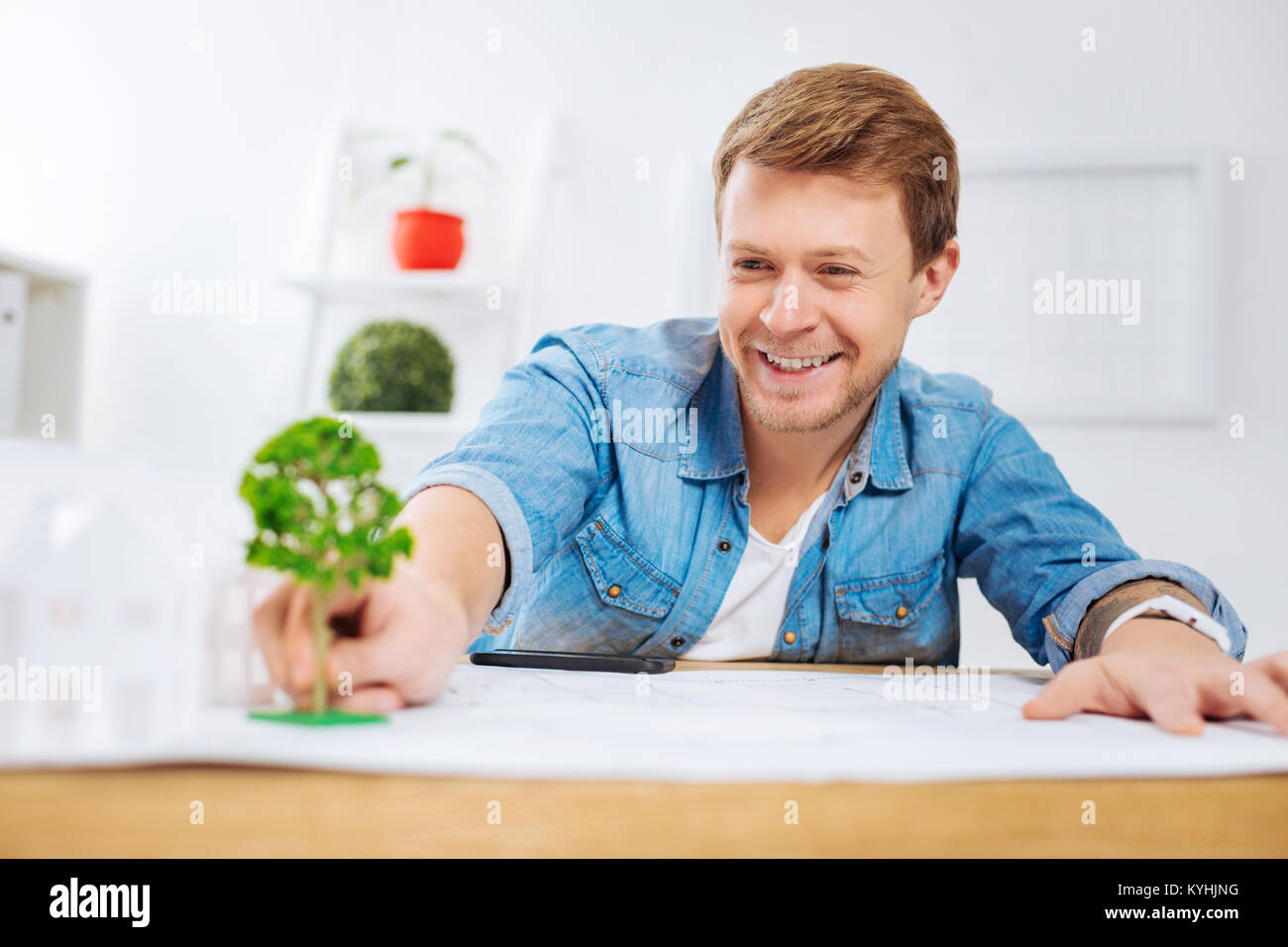 Happy engineer moving miniature trees while being at work Stock Photo ...