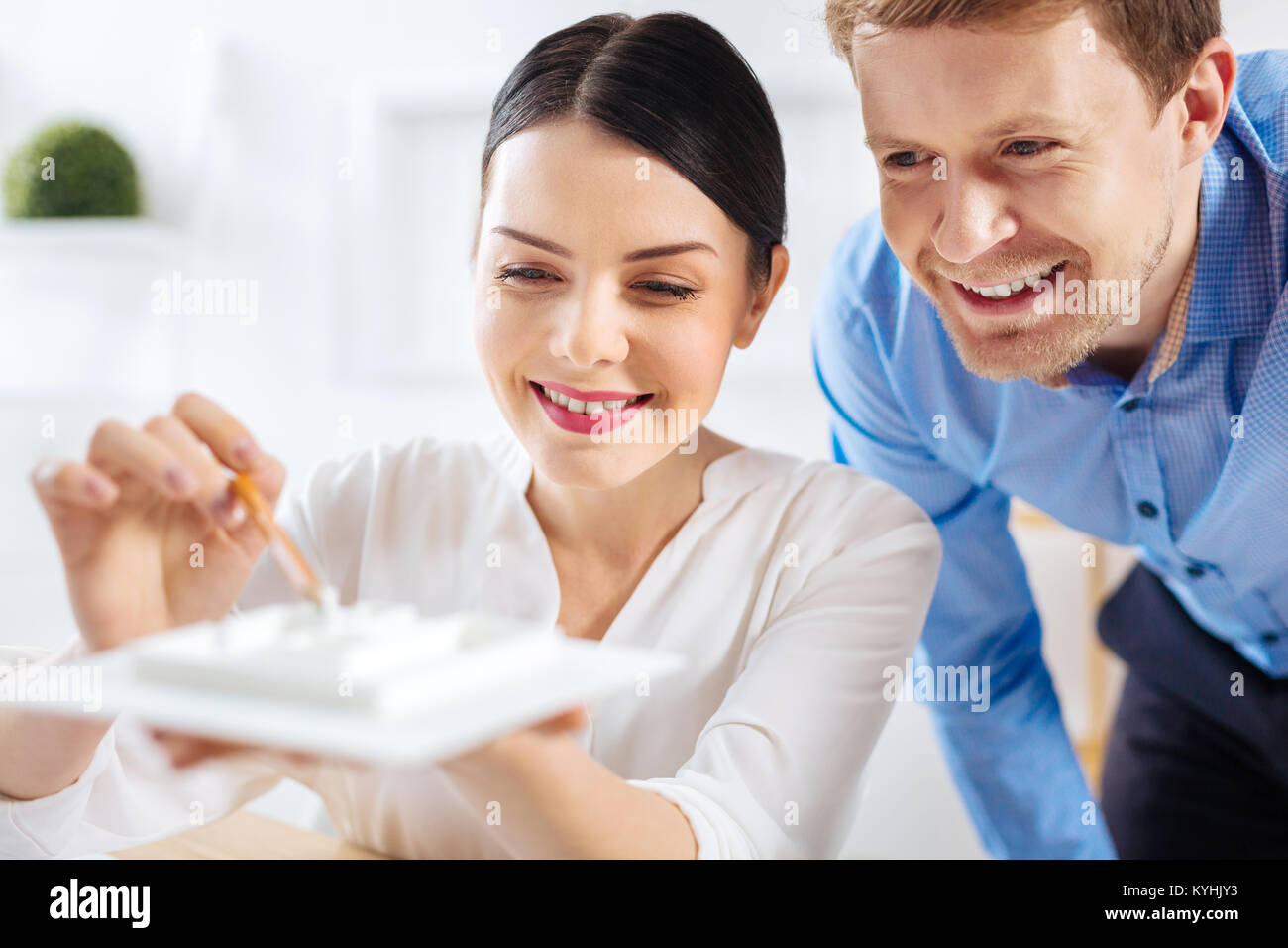 Smiling coworkers pointing to a miniature basis and feeling glad Stock ...