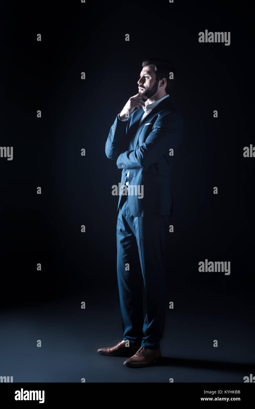 Intelligent handsome businessman standing against black background ...