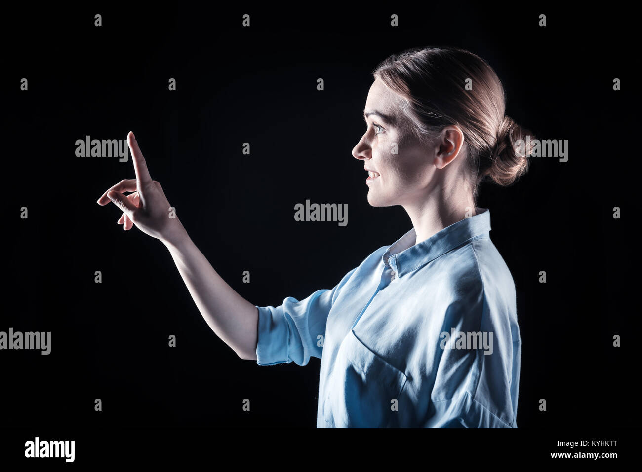 Joyful attractive woman standing half face against black background ...
