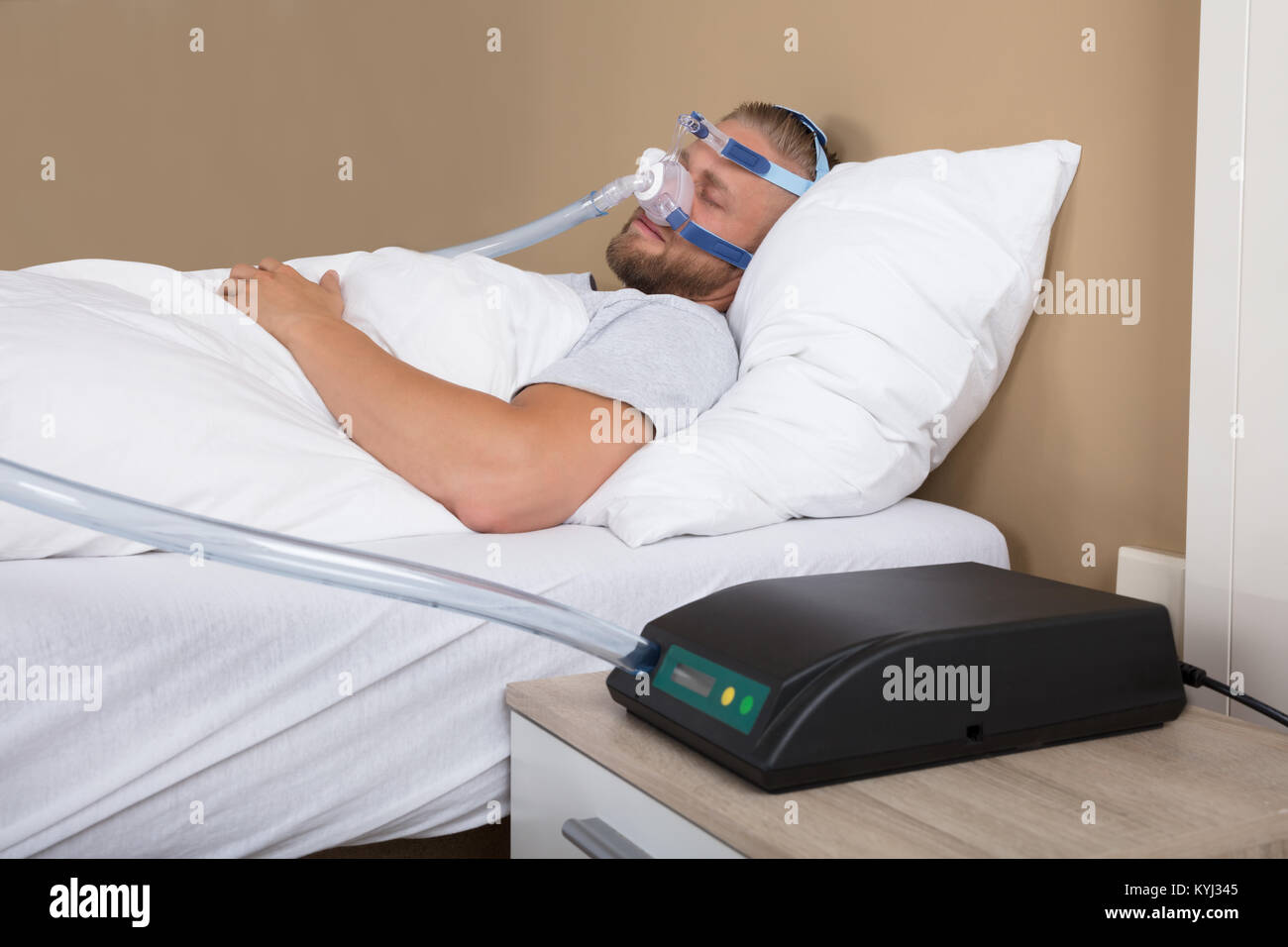 Young Man Lying On Bed With Sleeping Apnea And CPAP Machine Stock Photo ...