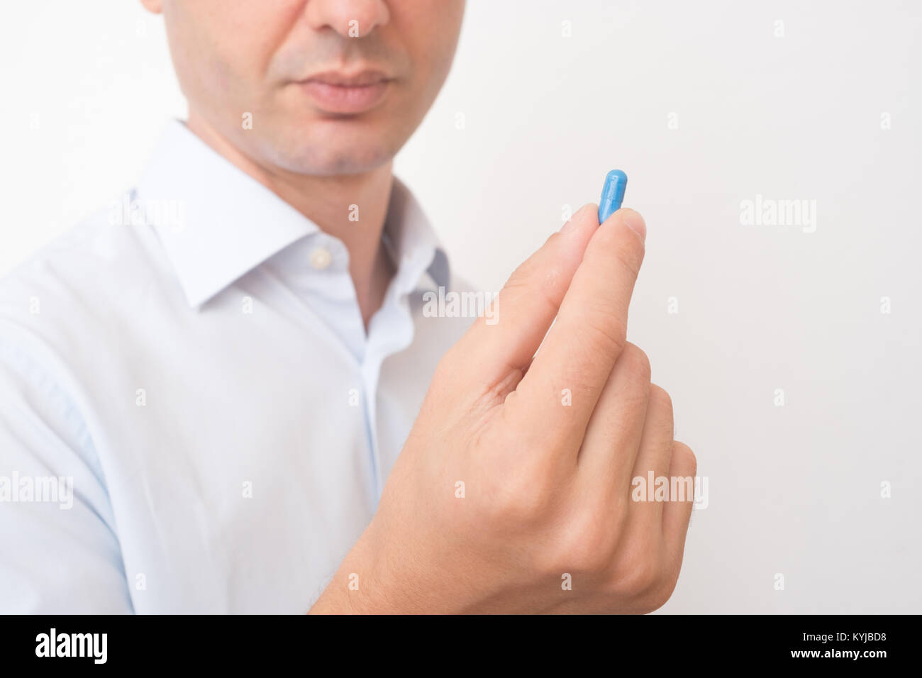 Head of ill man eating blue medicine pill Stock Photo - Alamy