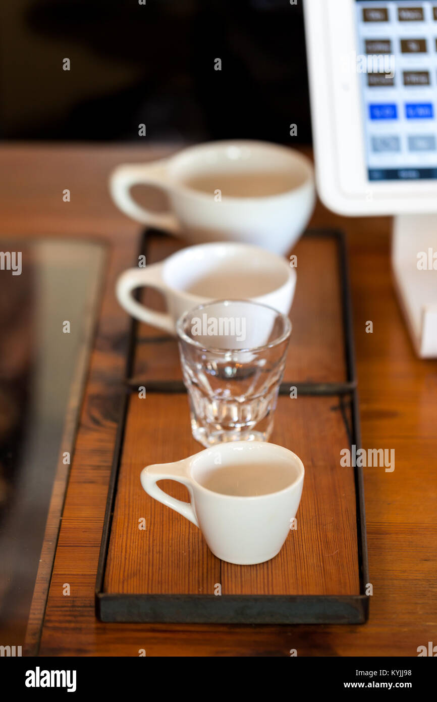 Coffee cups of various sizes next to tablet register in coffee shop on ...