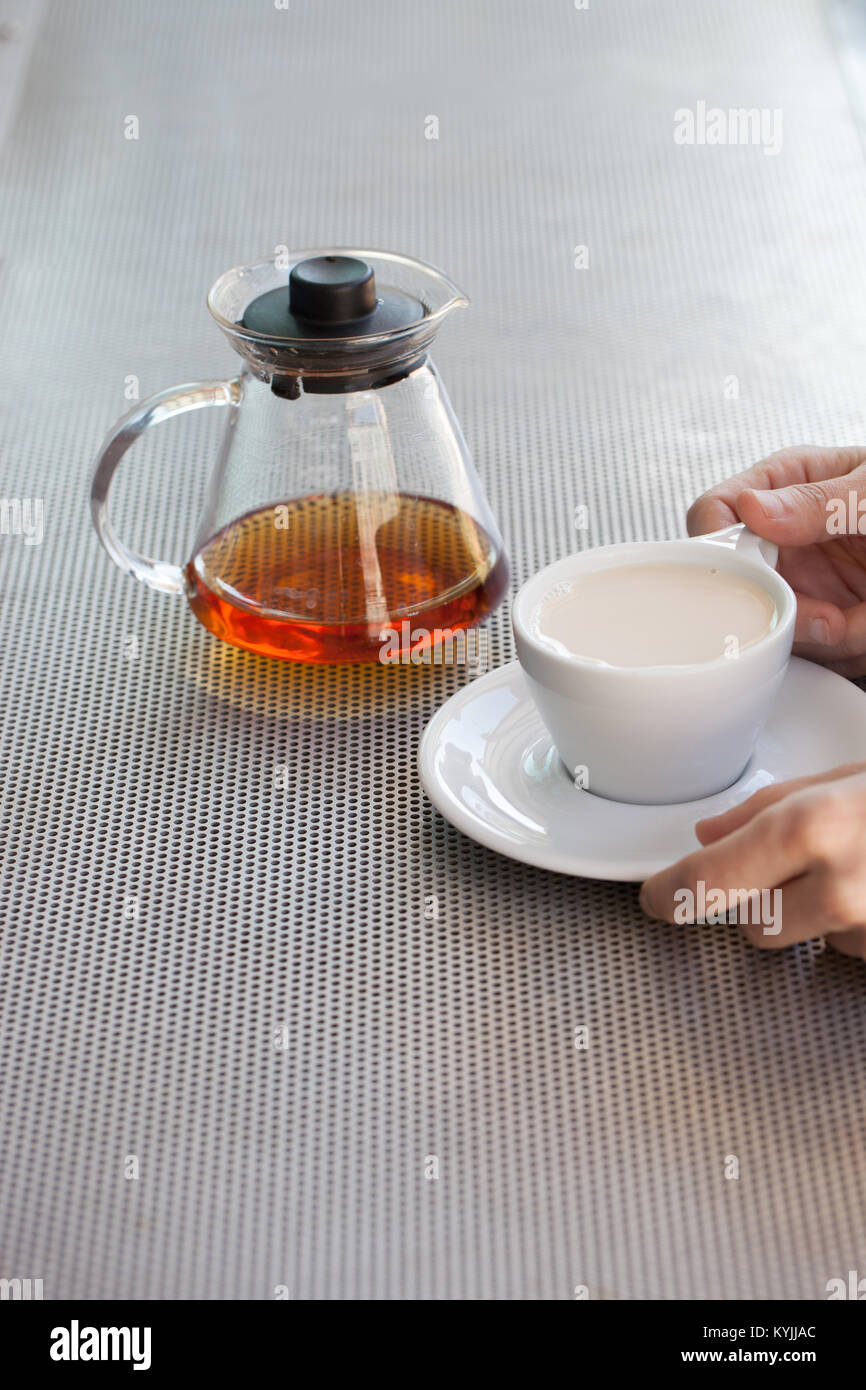 Caucasian woman hands hold ceramic cup with black tea and milk, glass ...