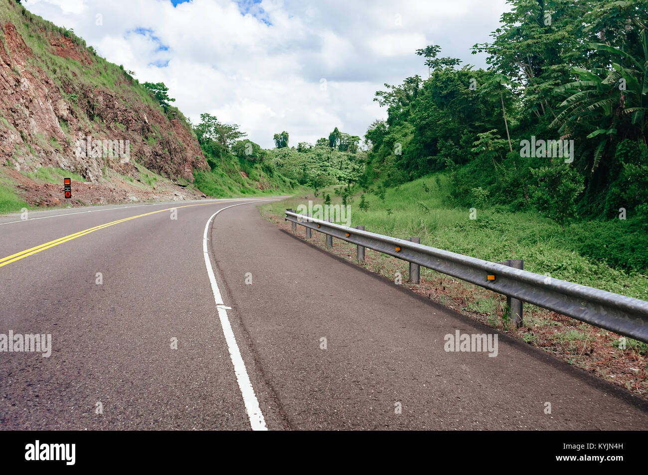 Road crossing the forest with cloudy sky and mountain view Stock Photo ...