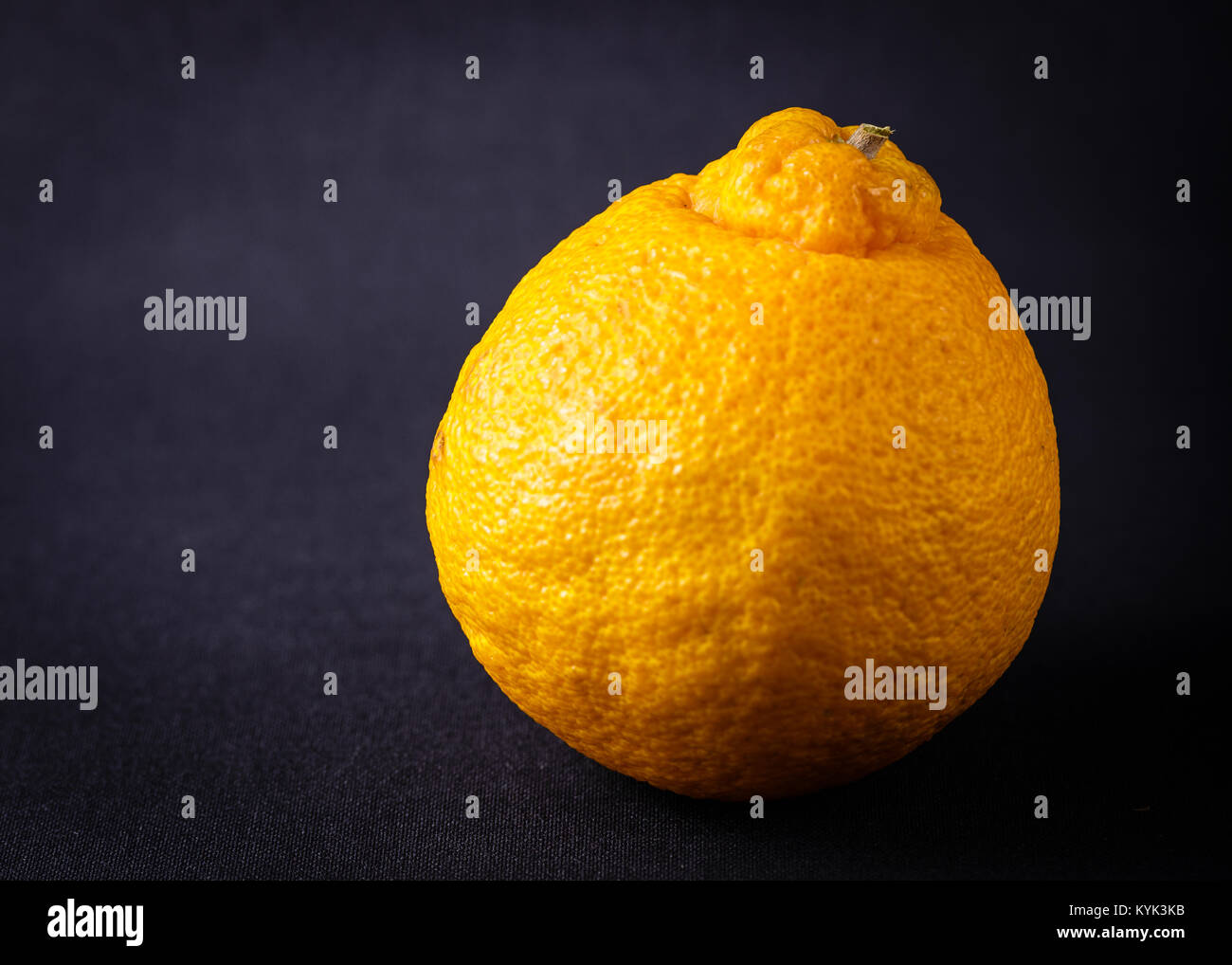 A whole mandarin orange on a black background Stock Photo - Alamy