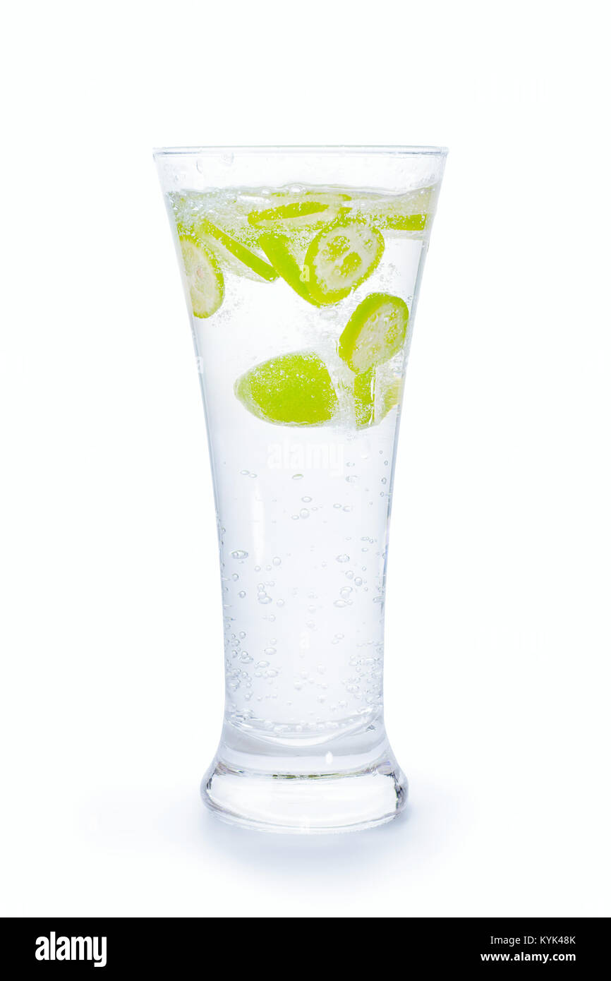 Small green citrus fruit slices into drinking glass full of water with splash and bubbles ...