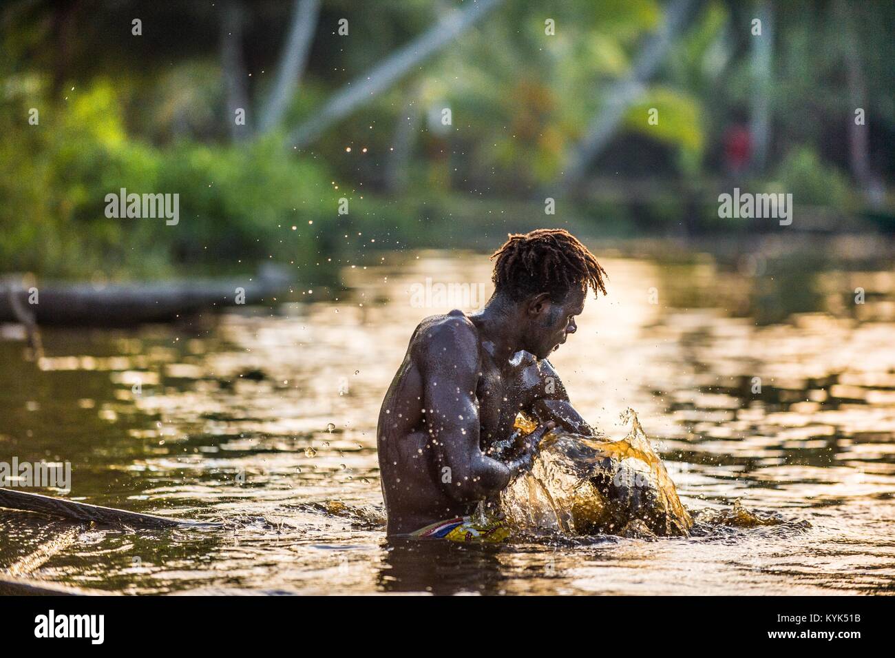 Asmat man is bathing in the river and wash away a body paint after the ...
