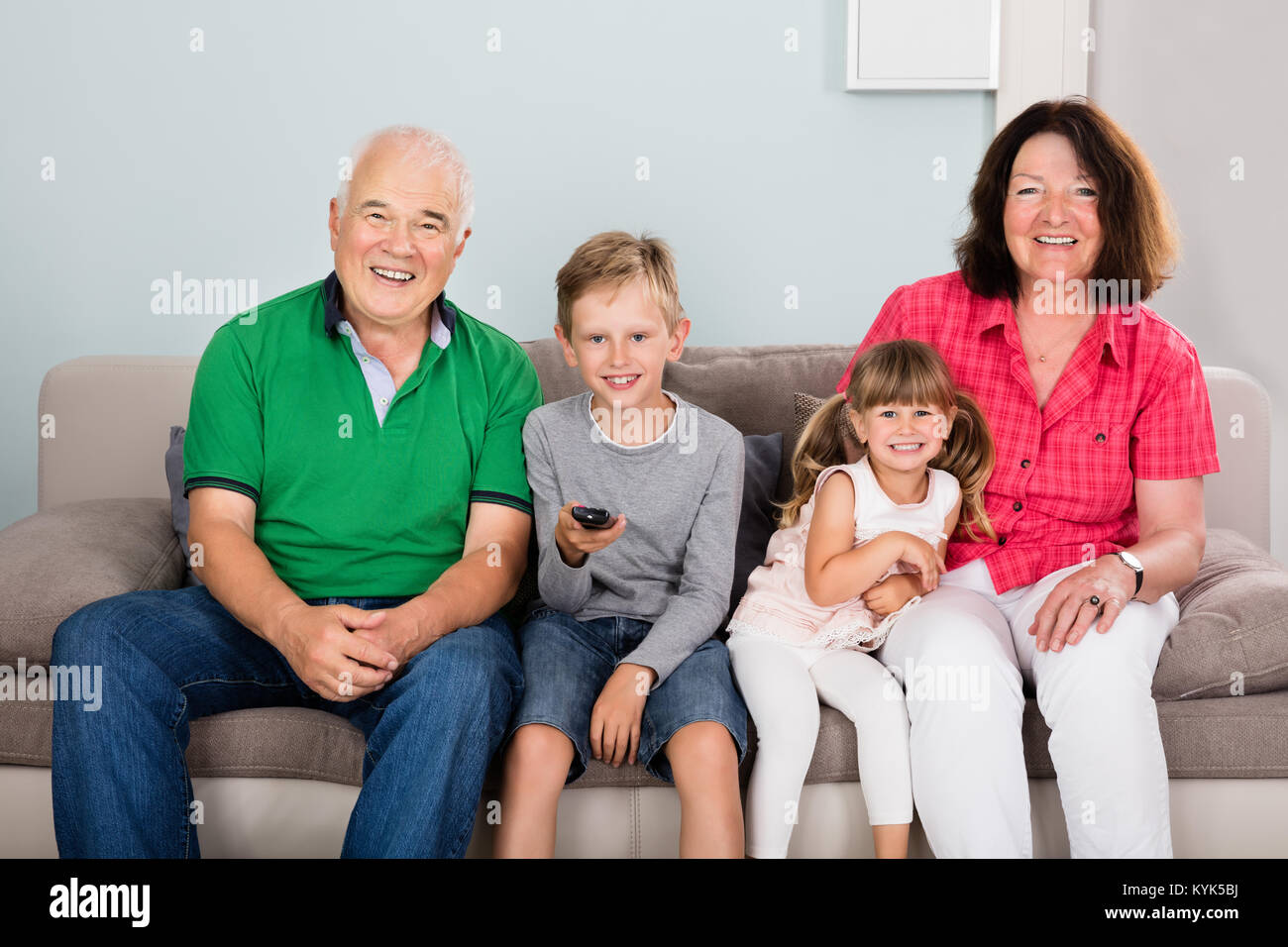 Happy Grandparents With Grandchildren Sitting On Couch In Living Room ...