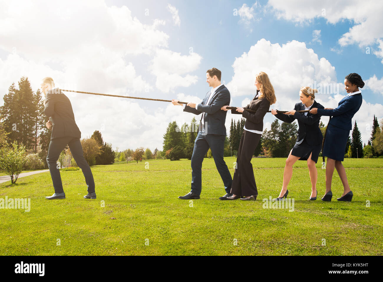 Group Of Business People Pulling A Rope In Opposite Direction At Park ...