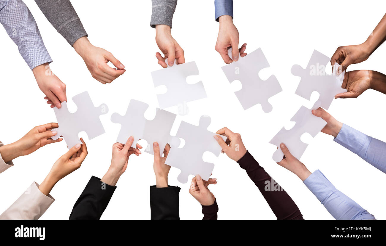 Elevated View Of Hands Holding White Jigsaw Puzzles Against White ...