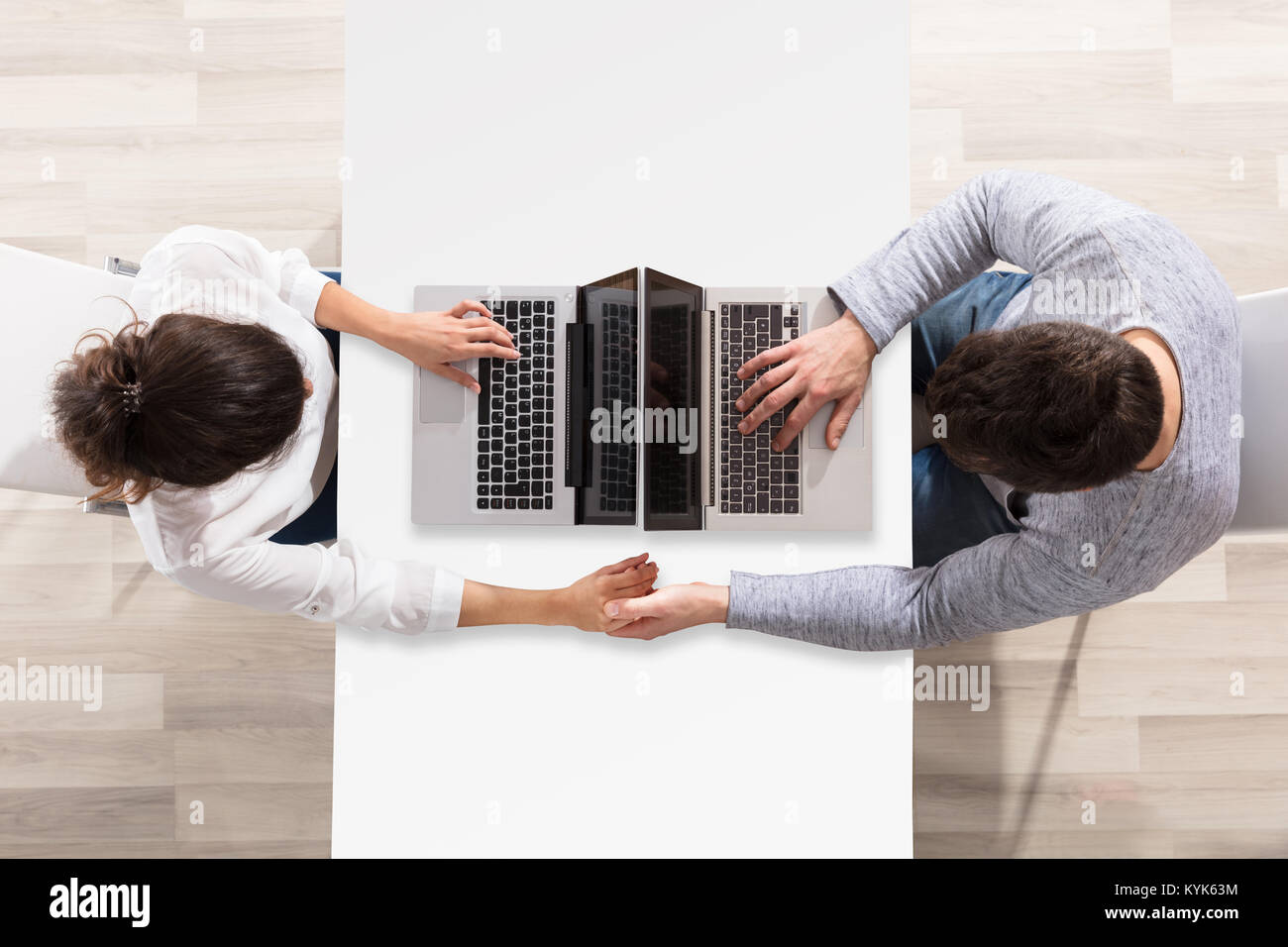 High Angle View Of Couple Sitting Face To Face Using Laptop Stock Photo ...