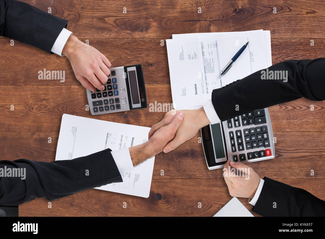Elevated View Of Two Businesspeople Shaking Hands With Invoice Over ...