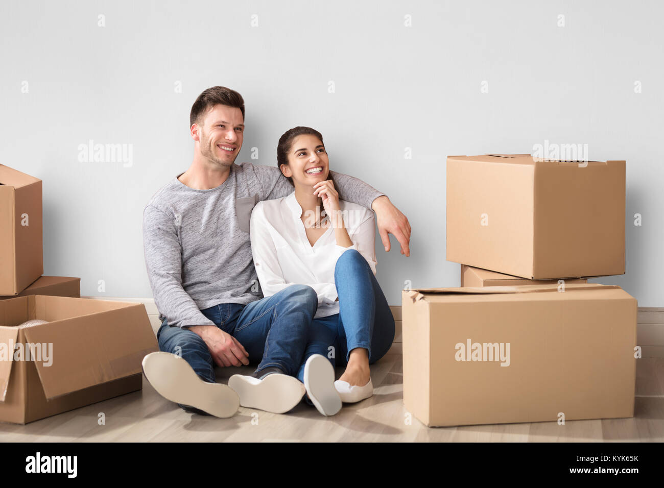 Happy Couple Sitting On Floor With Cardboard Boxes In Their New Home ...