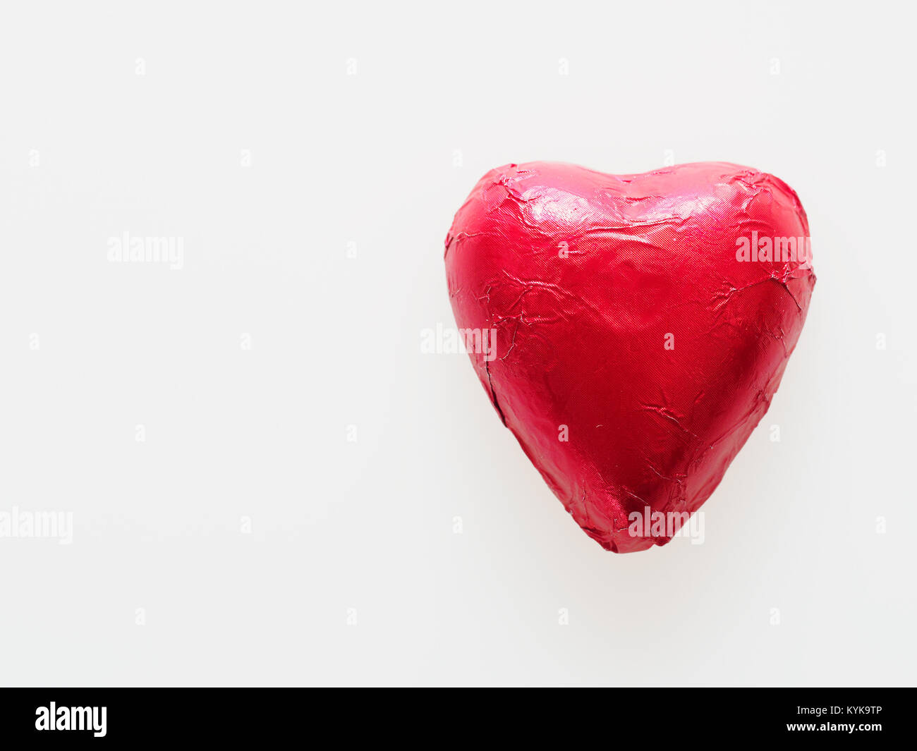 Heart shape chocolate wrapped in red foil isolated over white ...