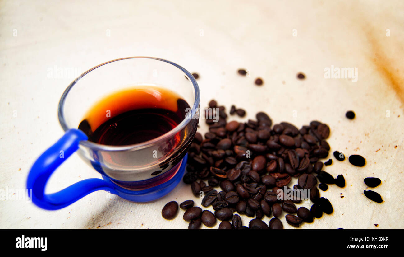 soft focus of a cup of energetic drink infusion and coffee beans with a ...
