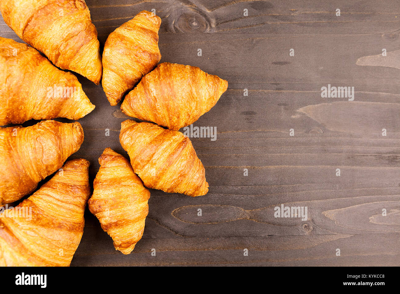 Mini and maxi croissants lying on wooden table Stock Photo - Alamy