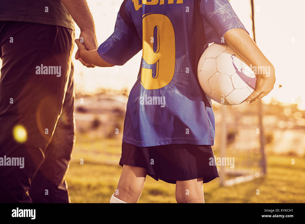 Mature man leading a young boy onto a soccer field Stock Photo - Alamy