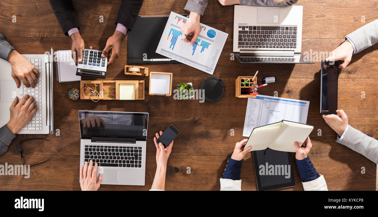 Overhead View Of Businesspeople Hands On Office Desk Using Electronic ...