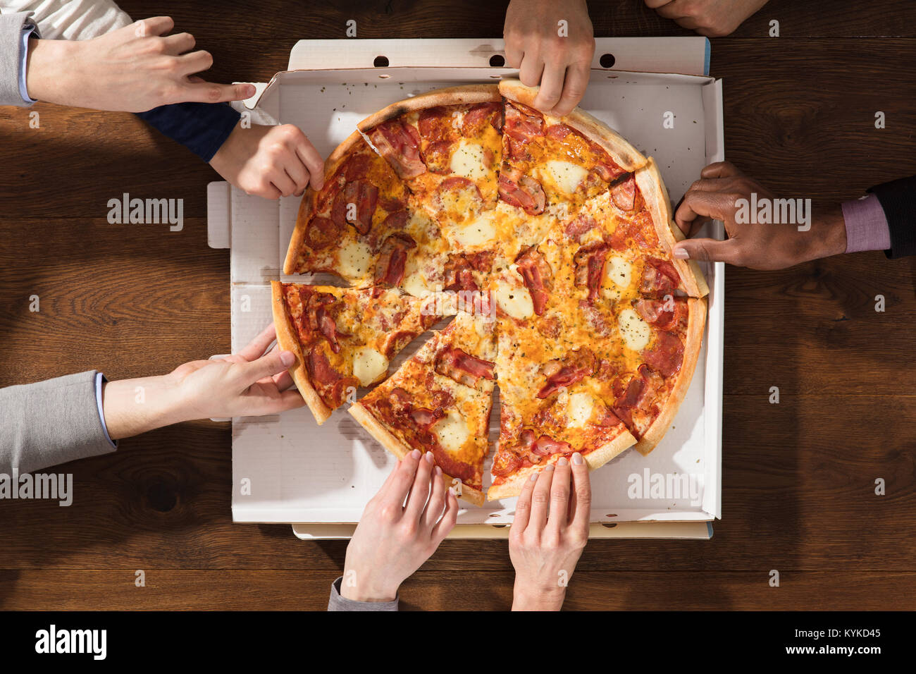 Group Of Hands Taking Each Slice Of Pizza From The Box Stock Photo - Alamy