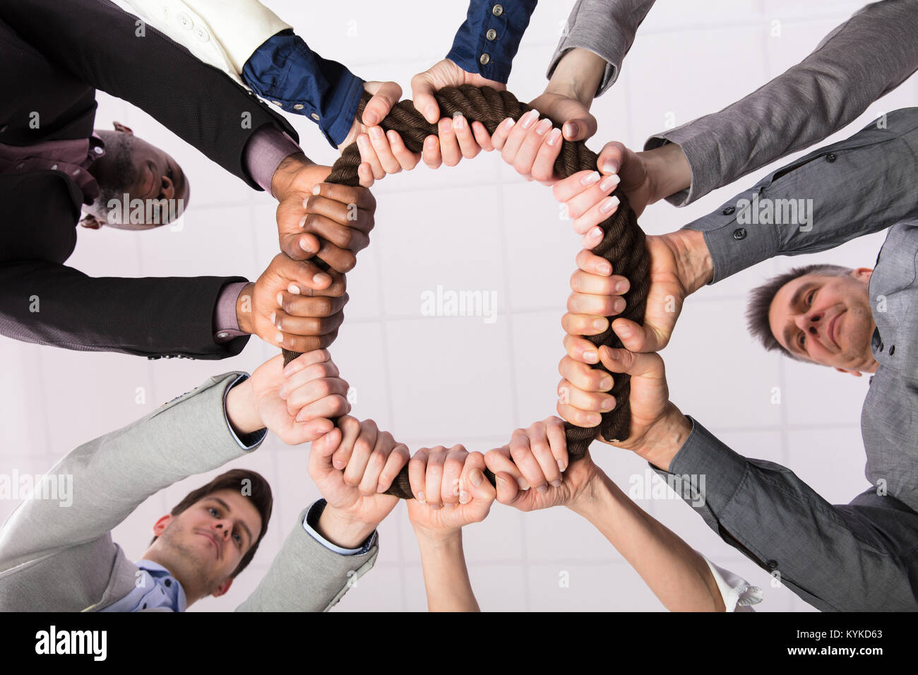 Businesspeople Standing In Circle Holding The Rope Together With Their ...