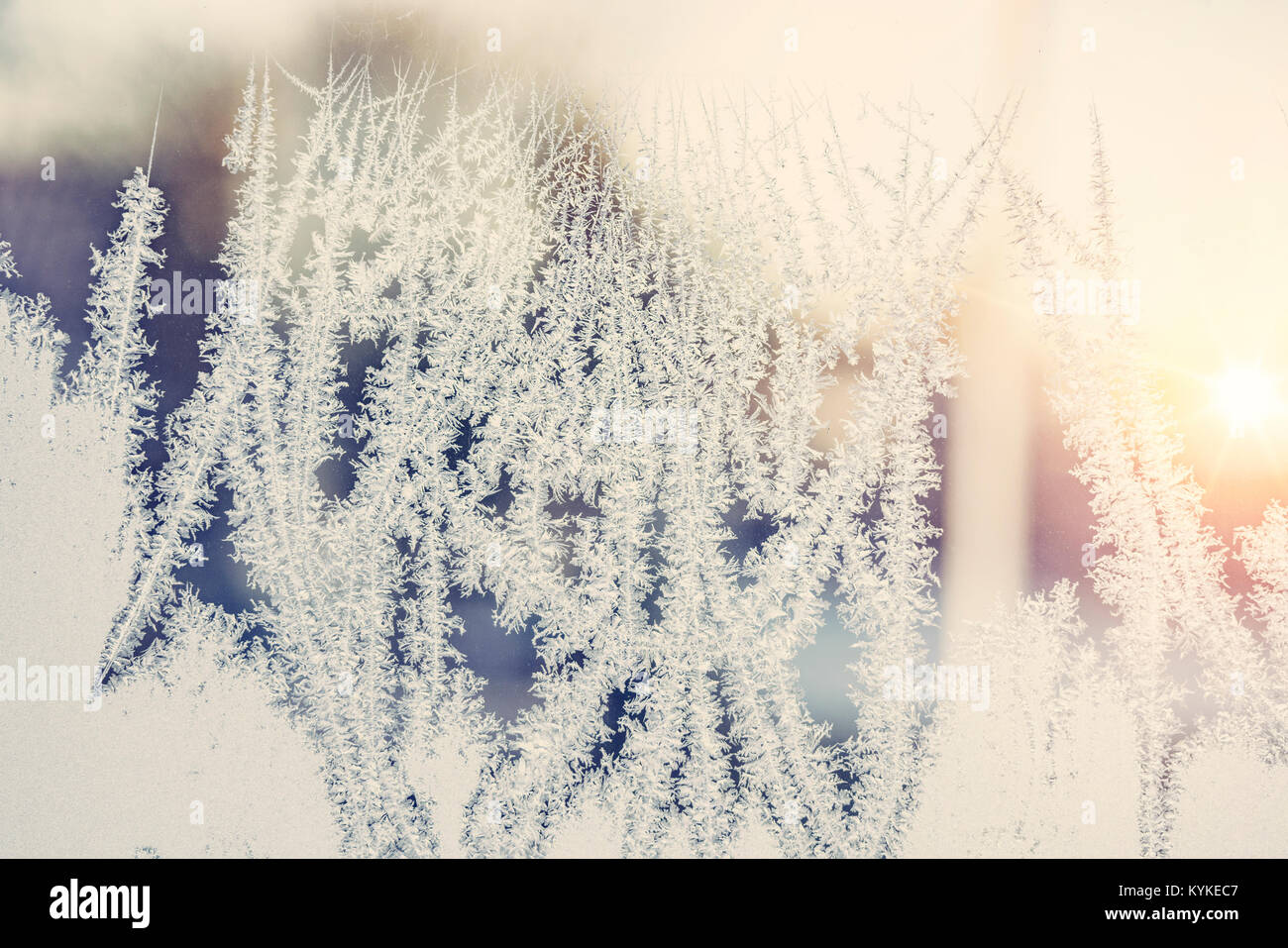 Sunrise behind a frosty window with beautiful frost patterns in the ...