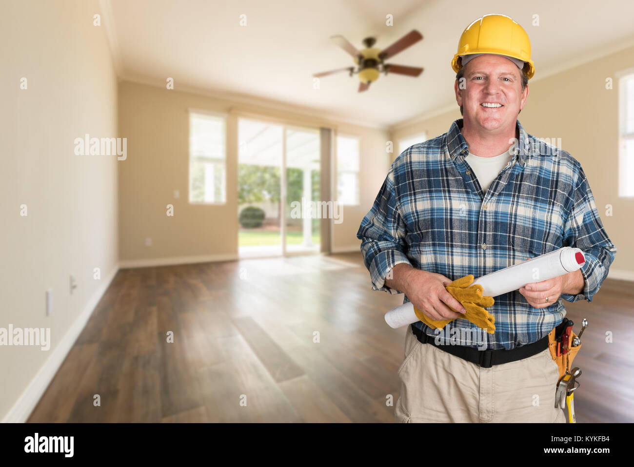 Contractor With Plans and Hard Hat Inside Empty Room with Wood Floors ...