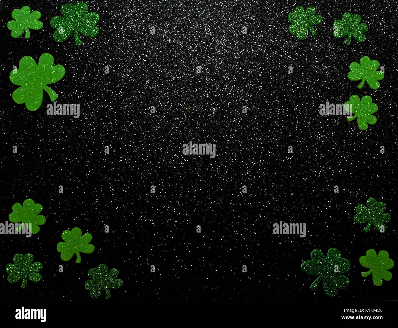 Different green colored shamrocks of various sizes on a shiny black ...