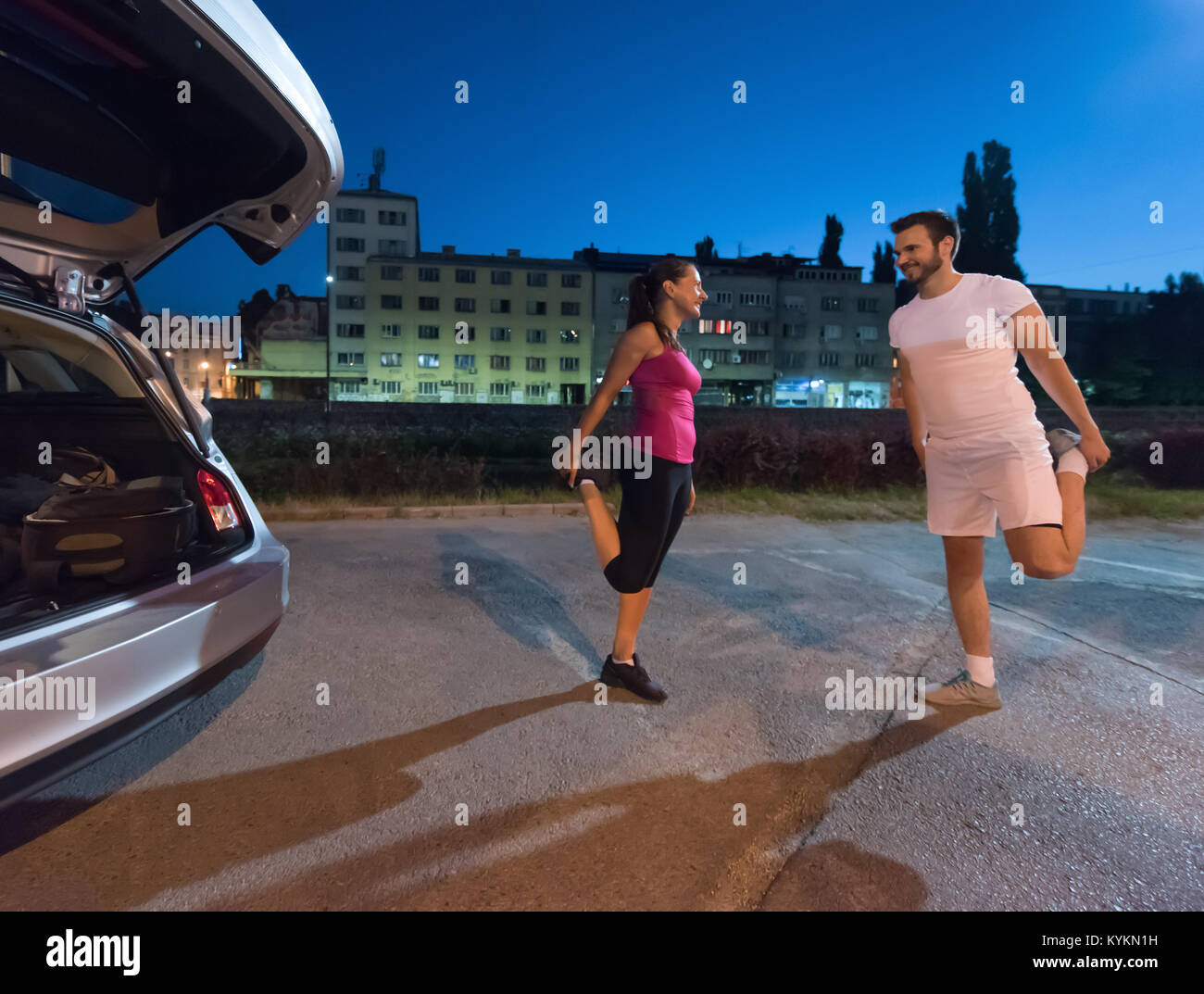 jogging couple warming up and stretching before evening running in the ...