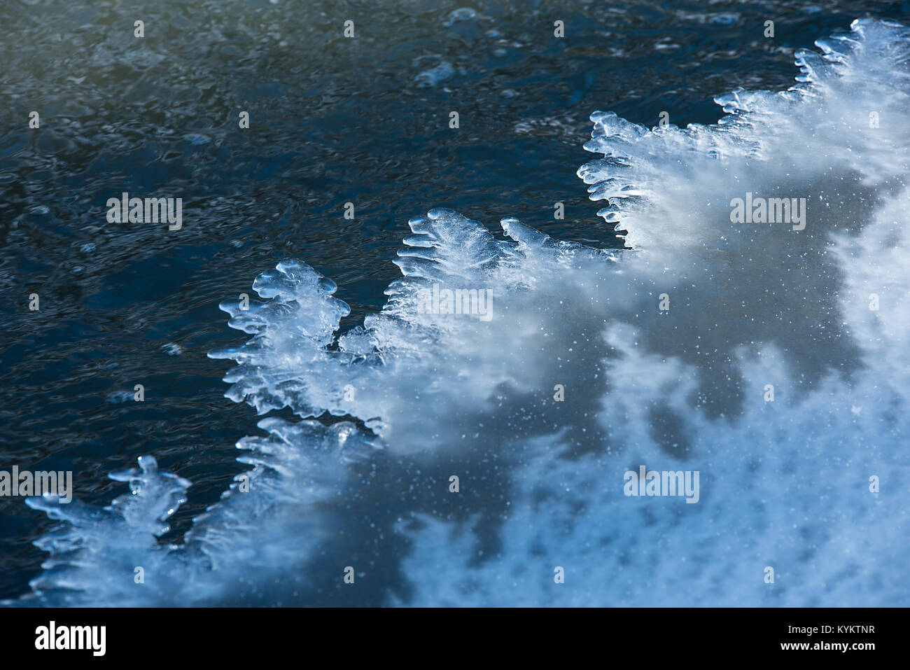 Water flowing under ice at the river; a running stream and ice ...