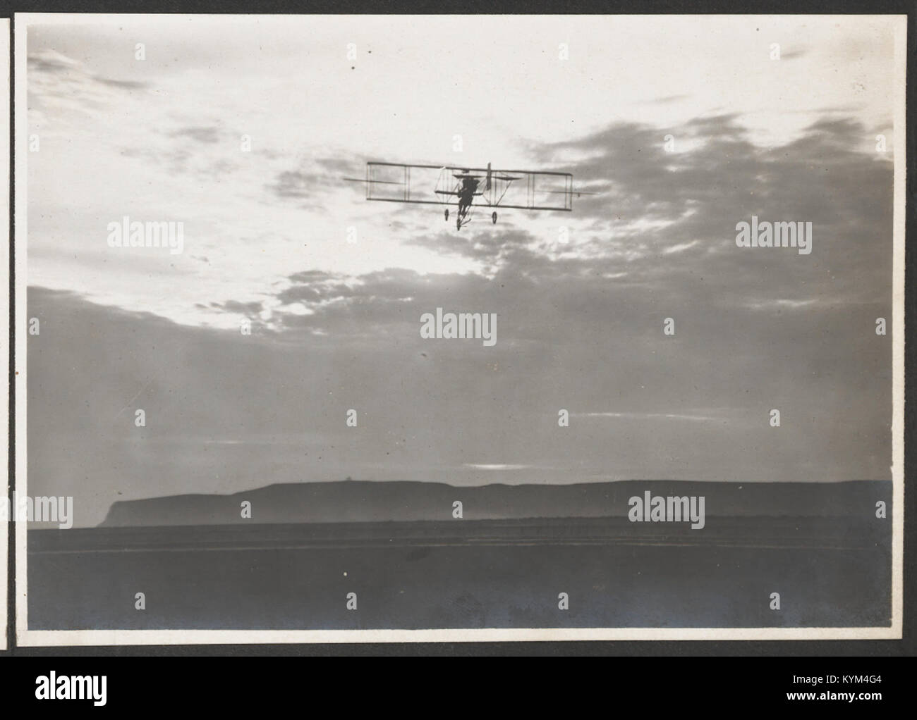 A historic photograph of a Curtiss Pusher biplane in flight at dusk ...