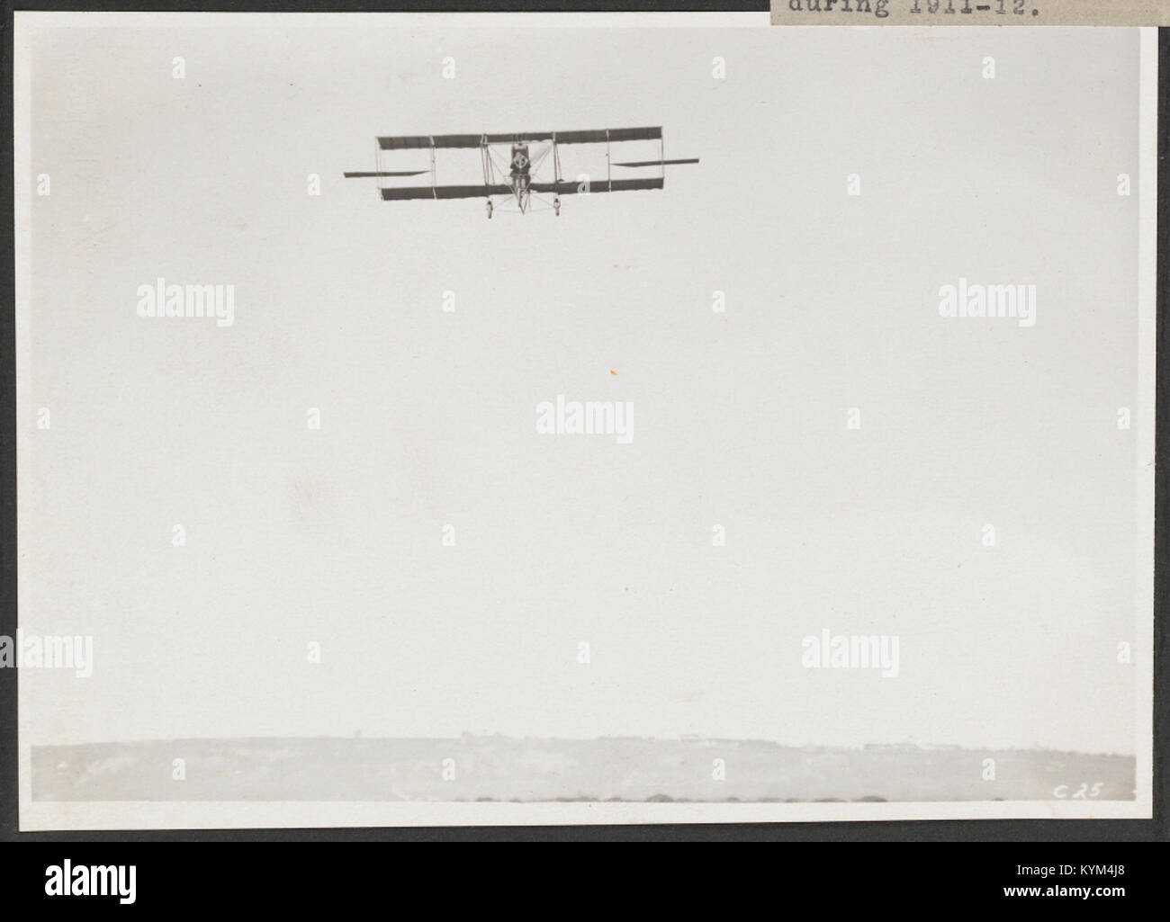 A historic photograph of a Curtiss Pusher biplane in flight, captured ...