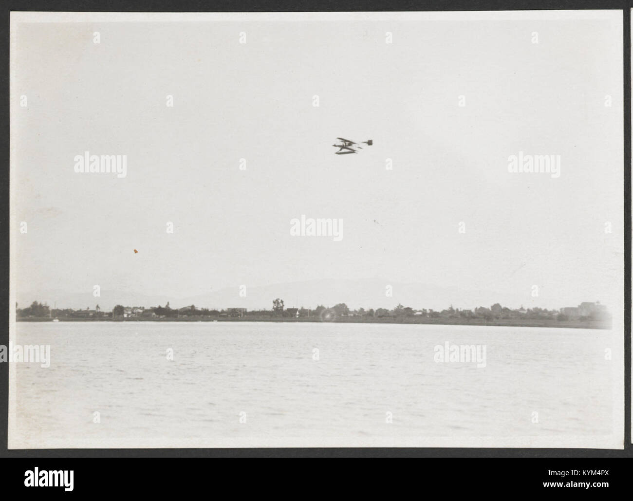A photograph of a Curtiss Pusher biplane flying above San Diego Bay ...