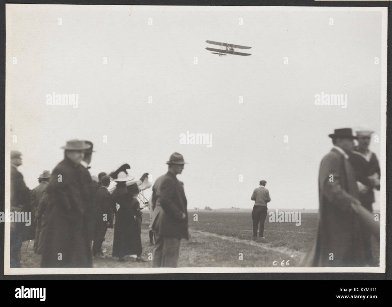 A biplane flying over a crowd of spectators, capturing a moment from ...