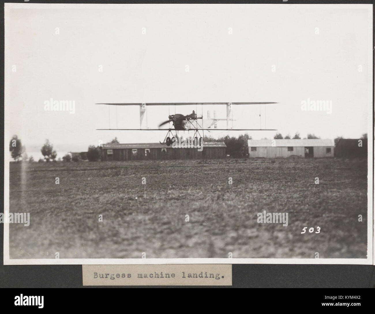 A historical photograph showing a Burgess aircraft landing. The image ...