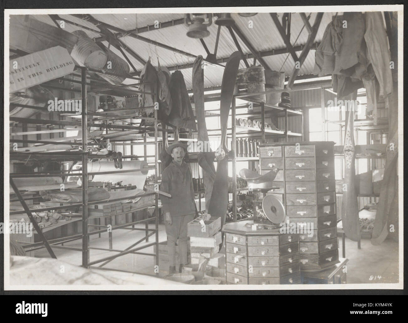 A photograph of a mechanic standing among parts in an airplane workshop ...