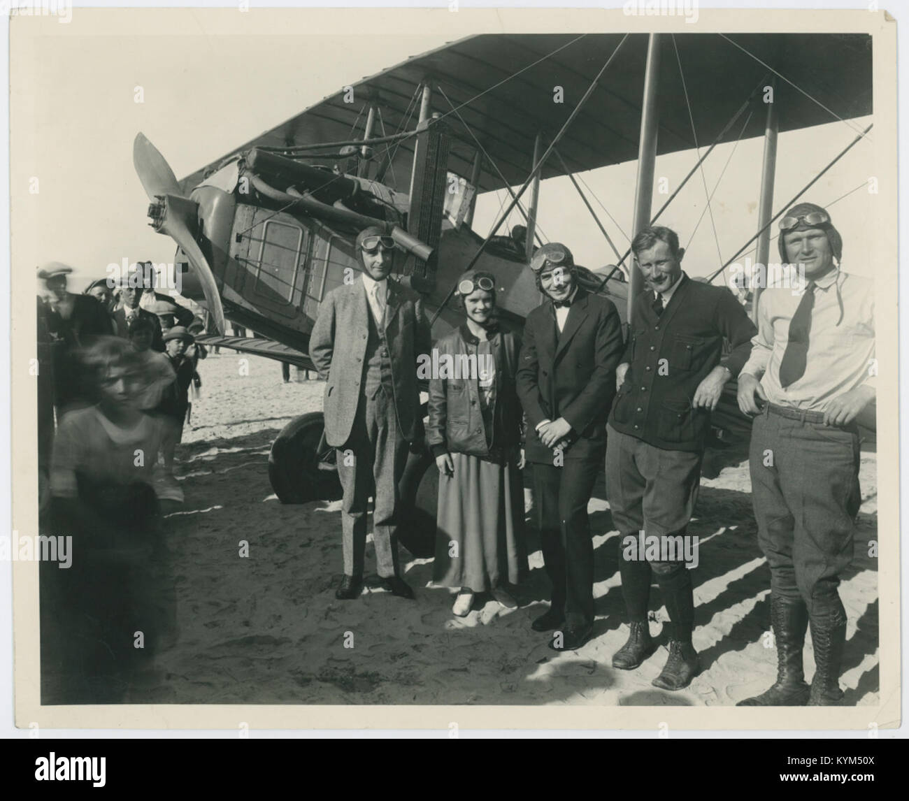 Photograph of a crowd posing with a biplane, showcasing early aviation ...