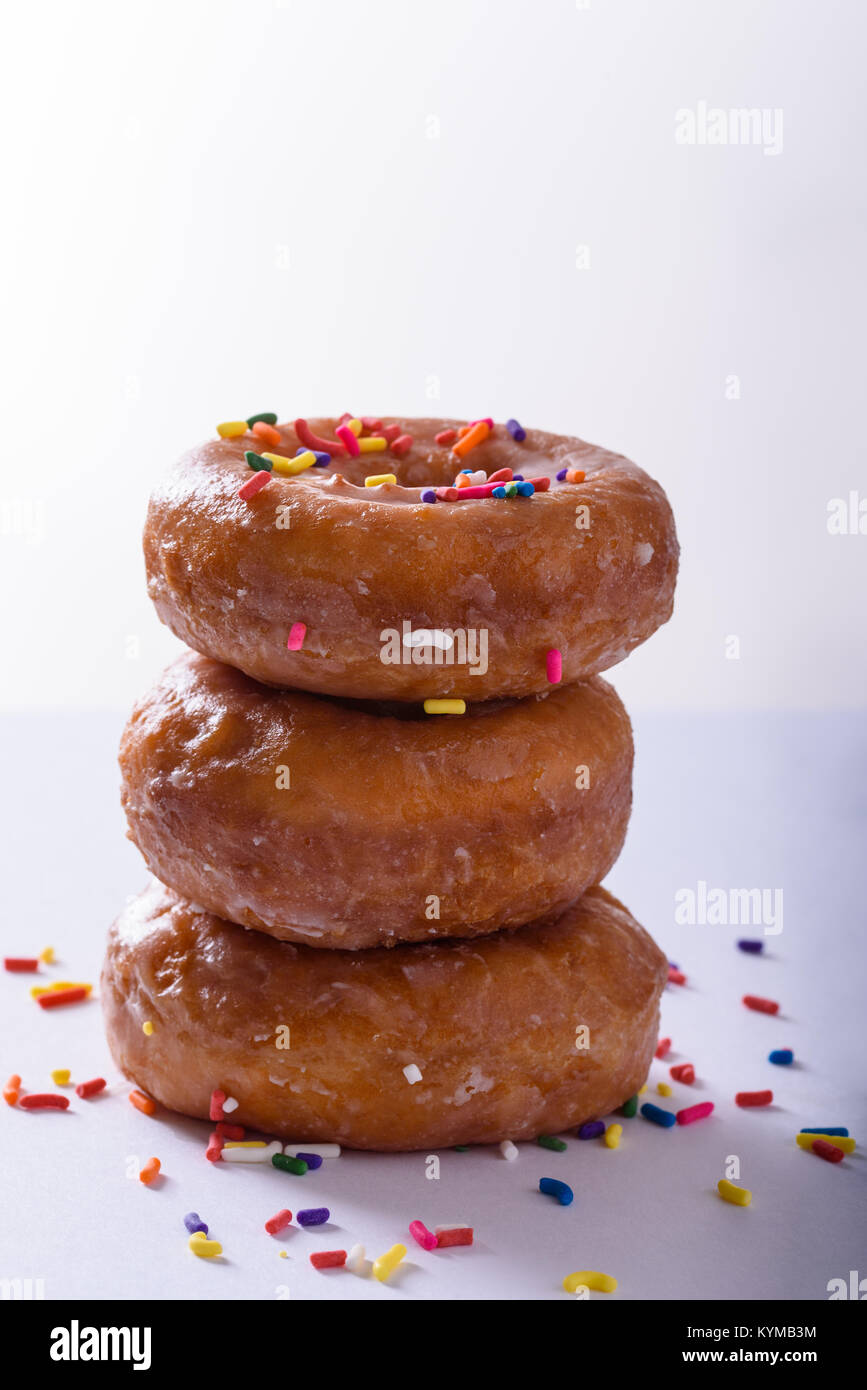 Stack of donuts with sprinkles on a white background Stock Photo - Alamy