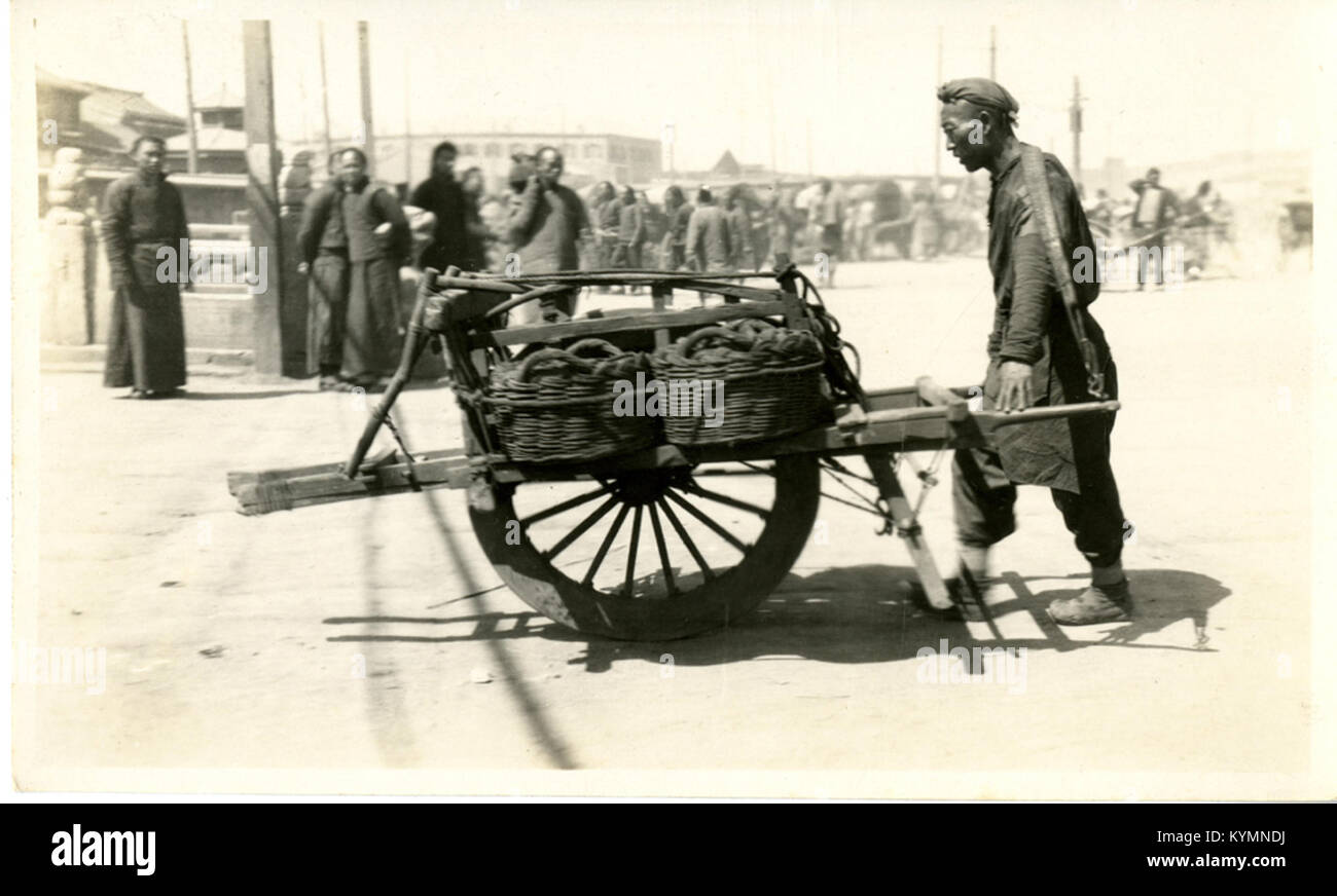 A photograph showing a Chinese man pushing a cart down a street in ...