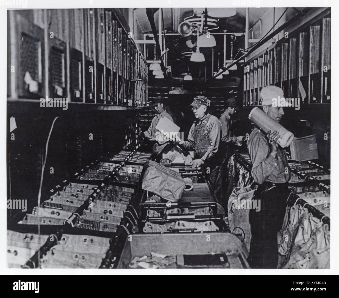 A historic photograph depicting railway post office clerks sorting mail ...