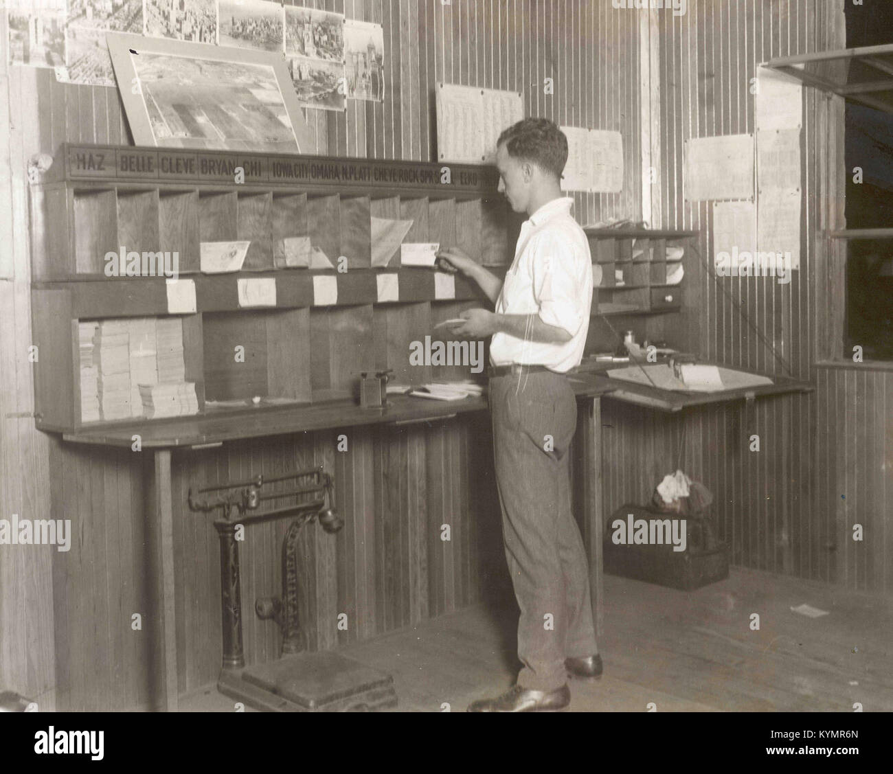 A historical photograph showing a postal worker sorting airmail in a ...