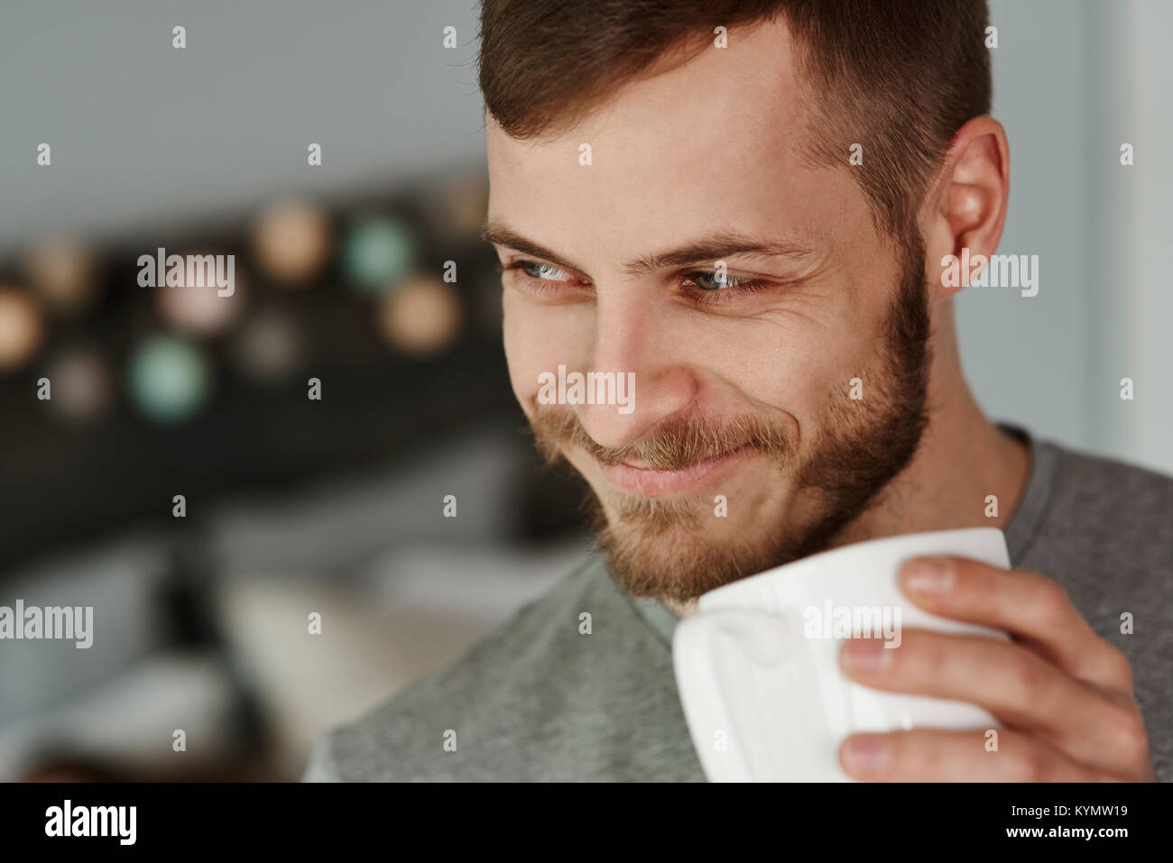 Smiling man drinking coffee at bedroom Stock Photo - Alamy