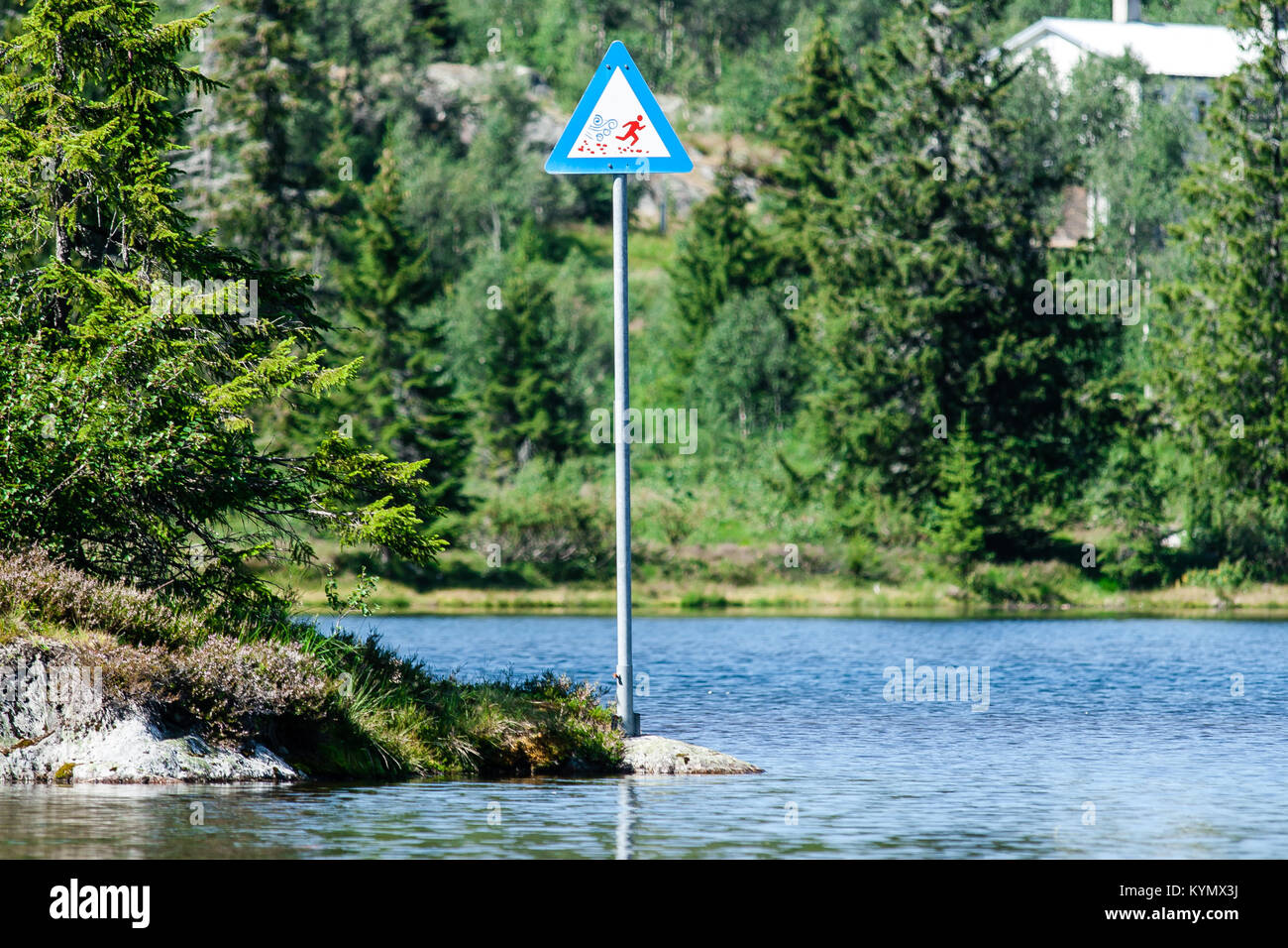 Warning sign post standing beside the lake in Norway showing that ...